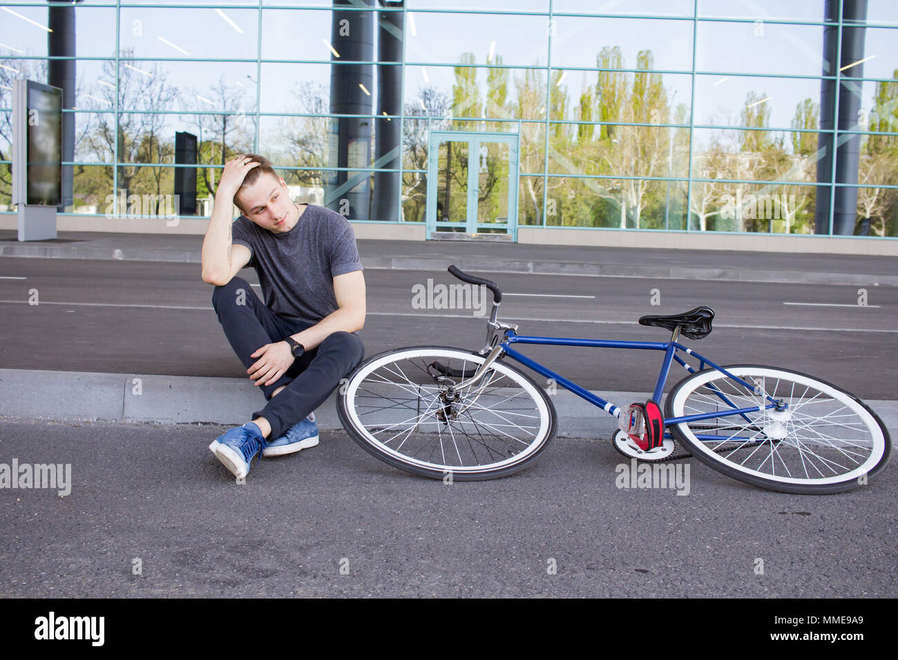 The guy in grey shirt on shop window background. a young man near blue ...