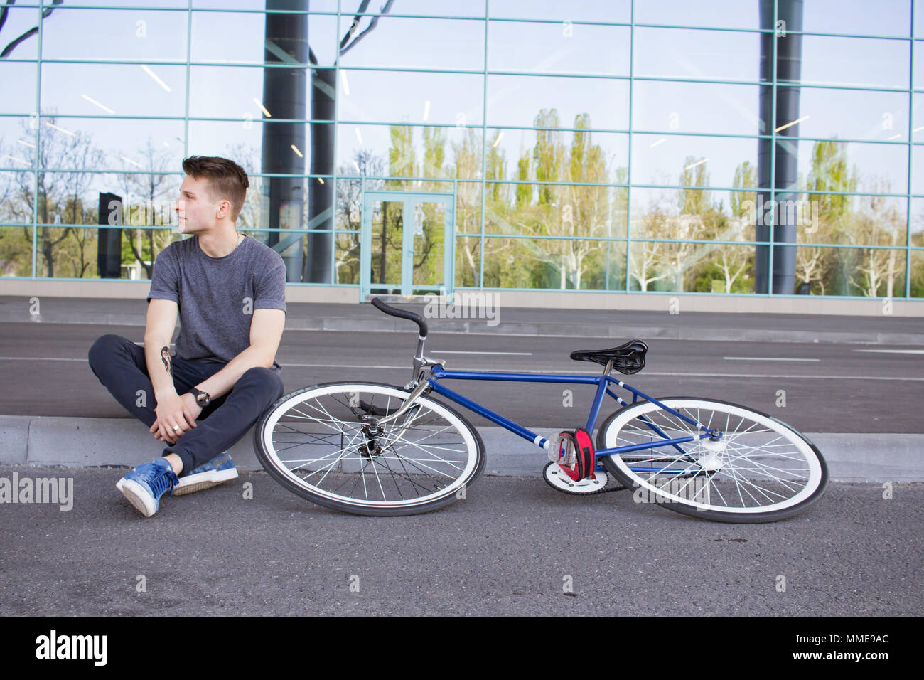 The guy in grey shirt on shop window background. a young man near blue ...