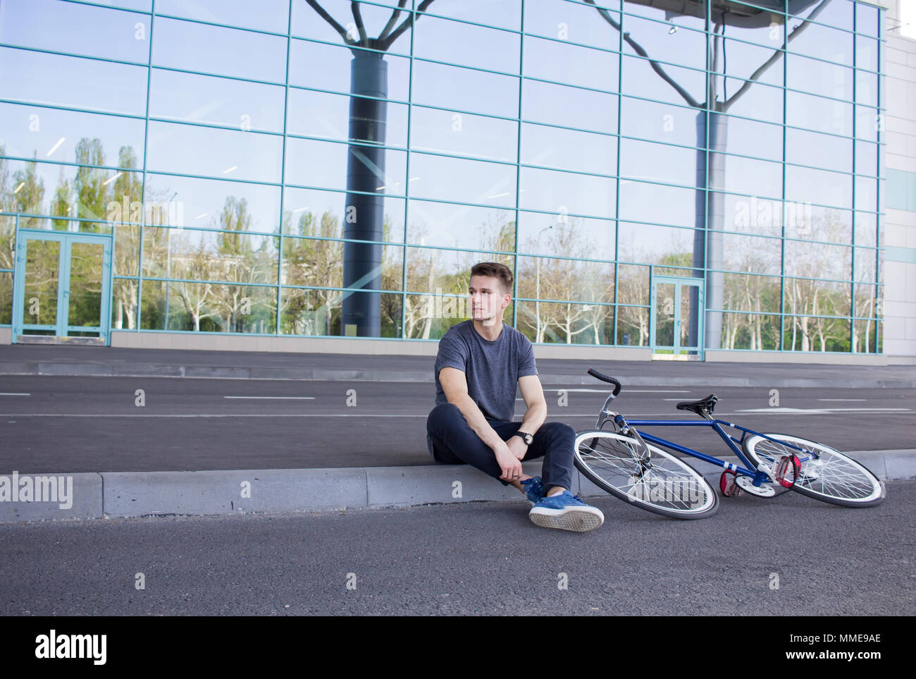 The guy in grey shirt on shop window background. a young man near blue ...