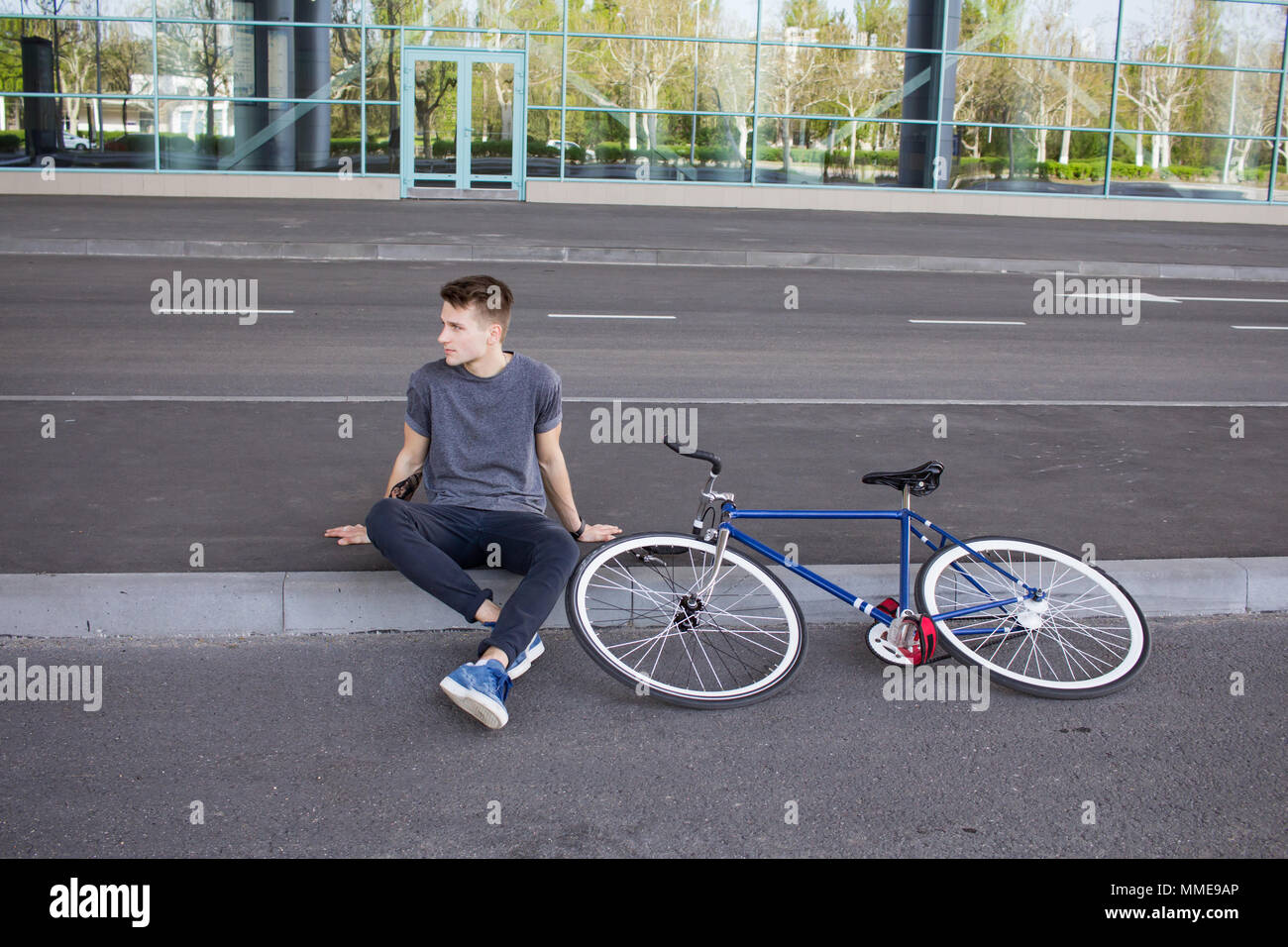 The guy in grey shirt on shop window background. a young man near blue ...