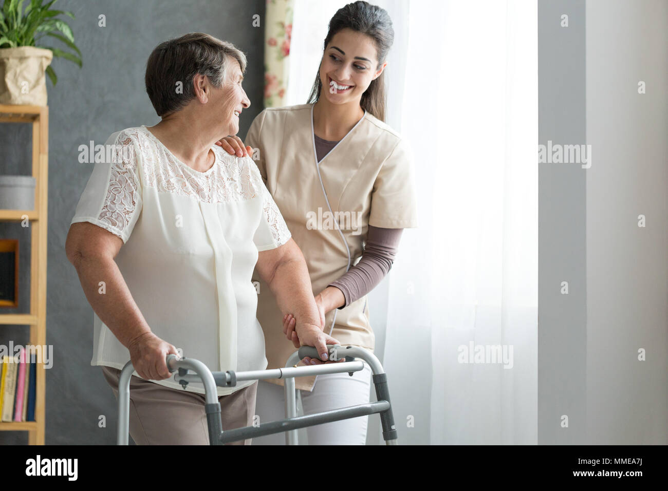 Smiling nurse helping senior lady to walk around the nursing home Stock ...