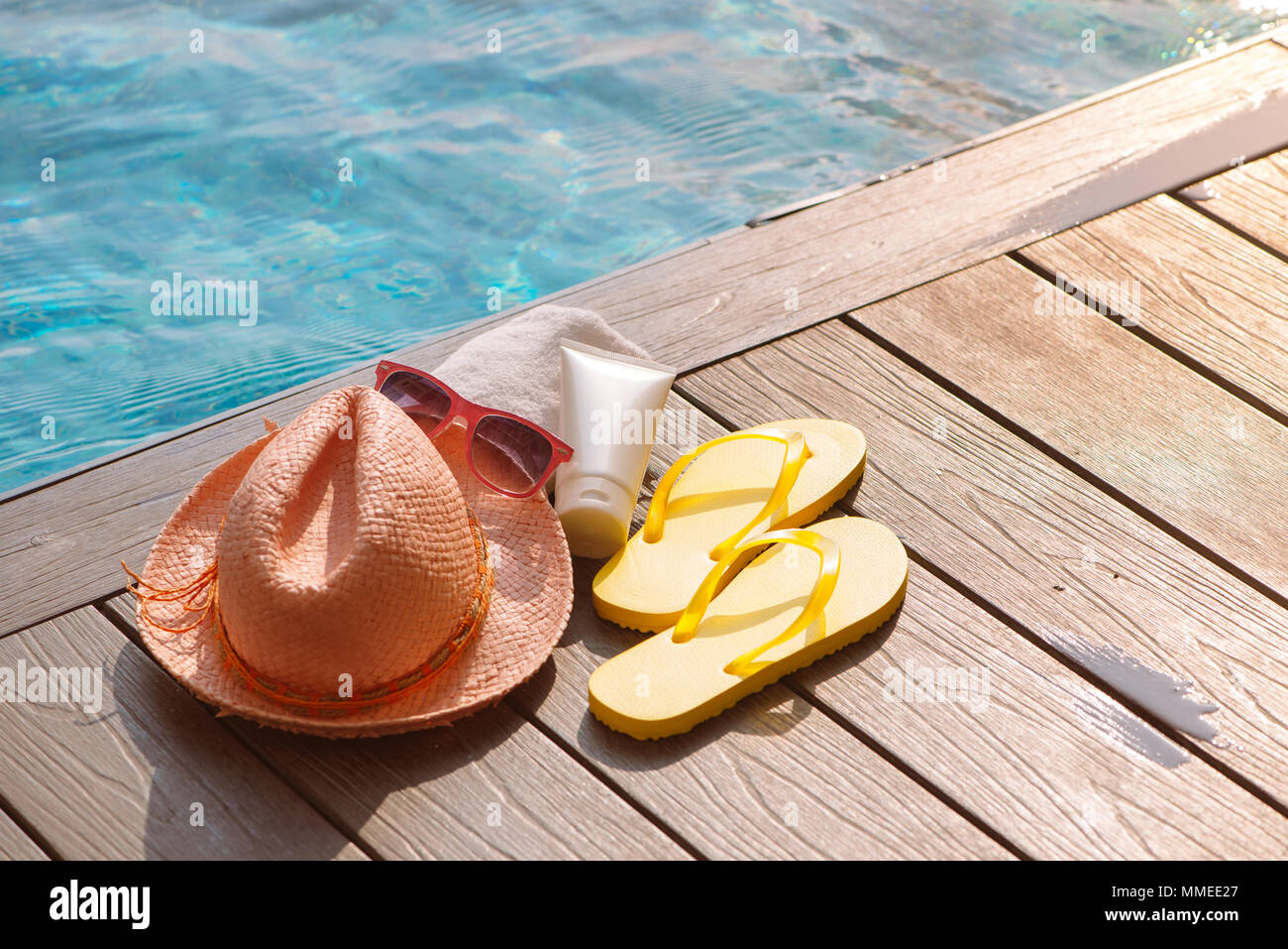 Hat, sunglasses and sunscreen at the side of swimming pool, summer ...