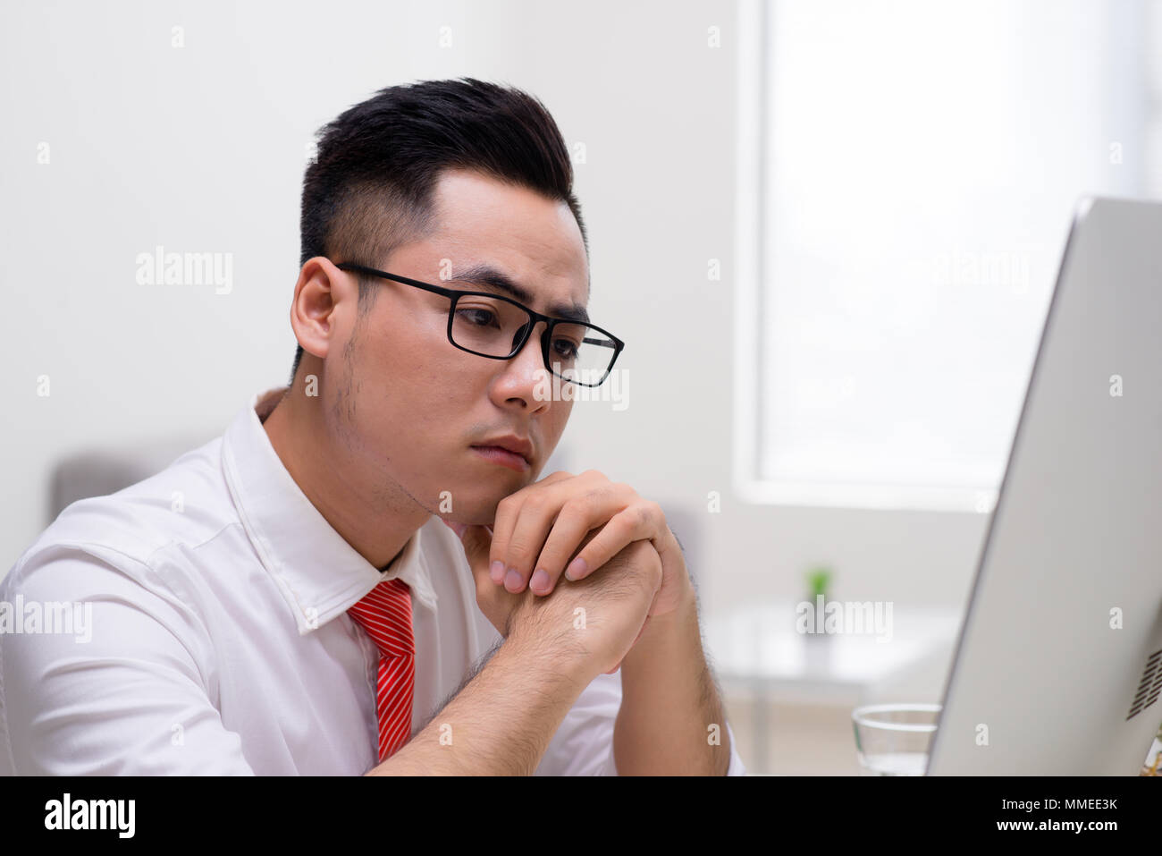 Young stylish worker at office working with computer and thinking how ...