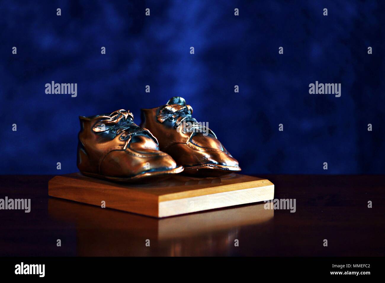 Bronzed baby shoes on plaque with blue background Stock Photo - Alamy