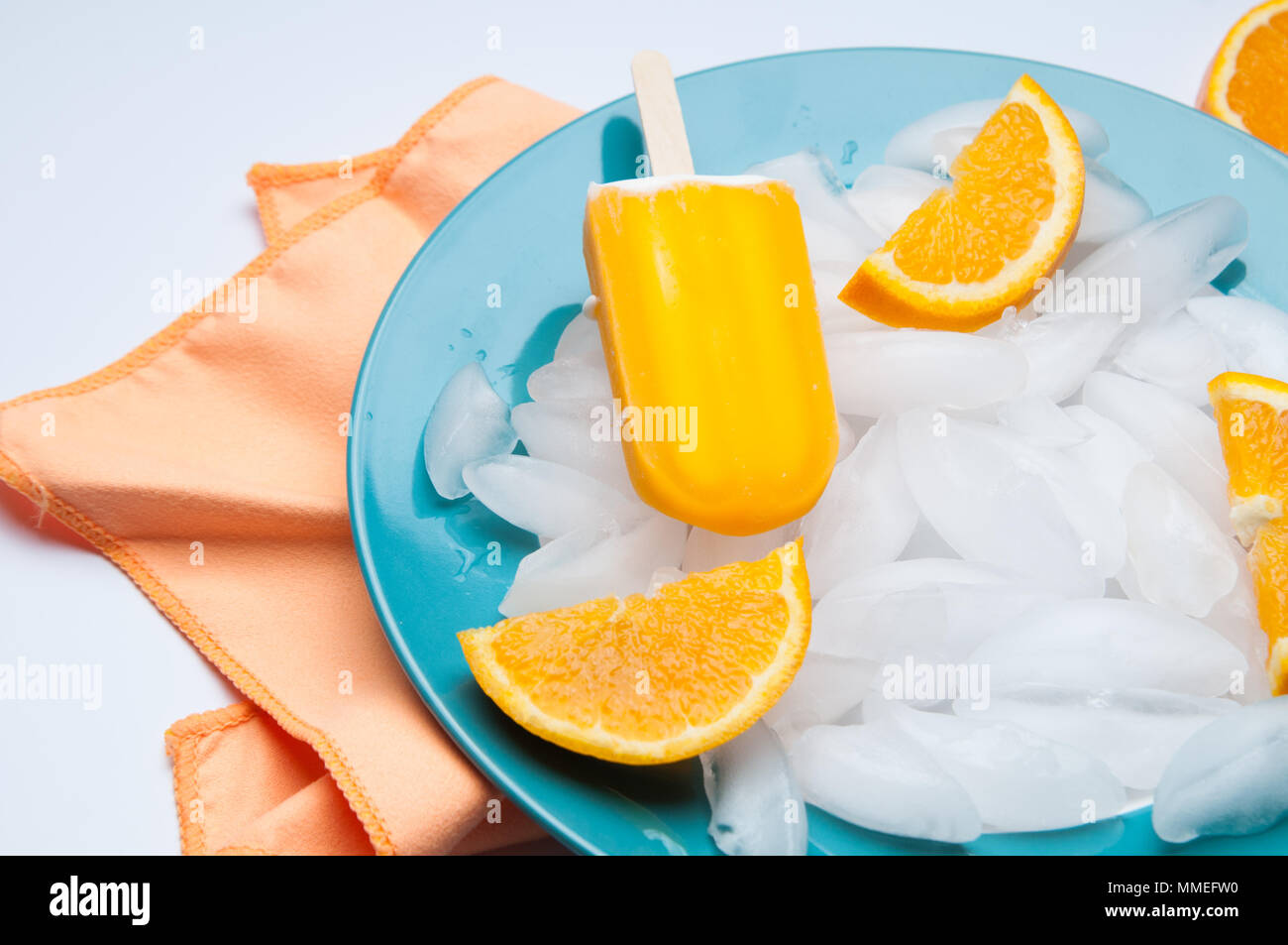 Orange popsicle on a plate of ice cubes Stock Photo - Alamy
