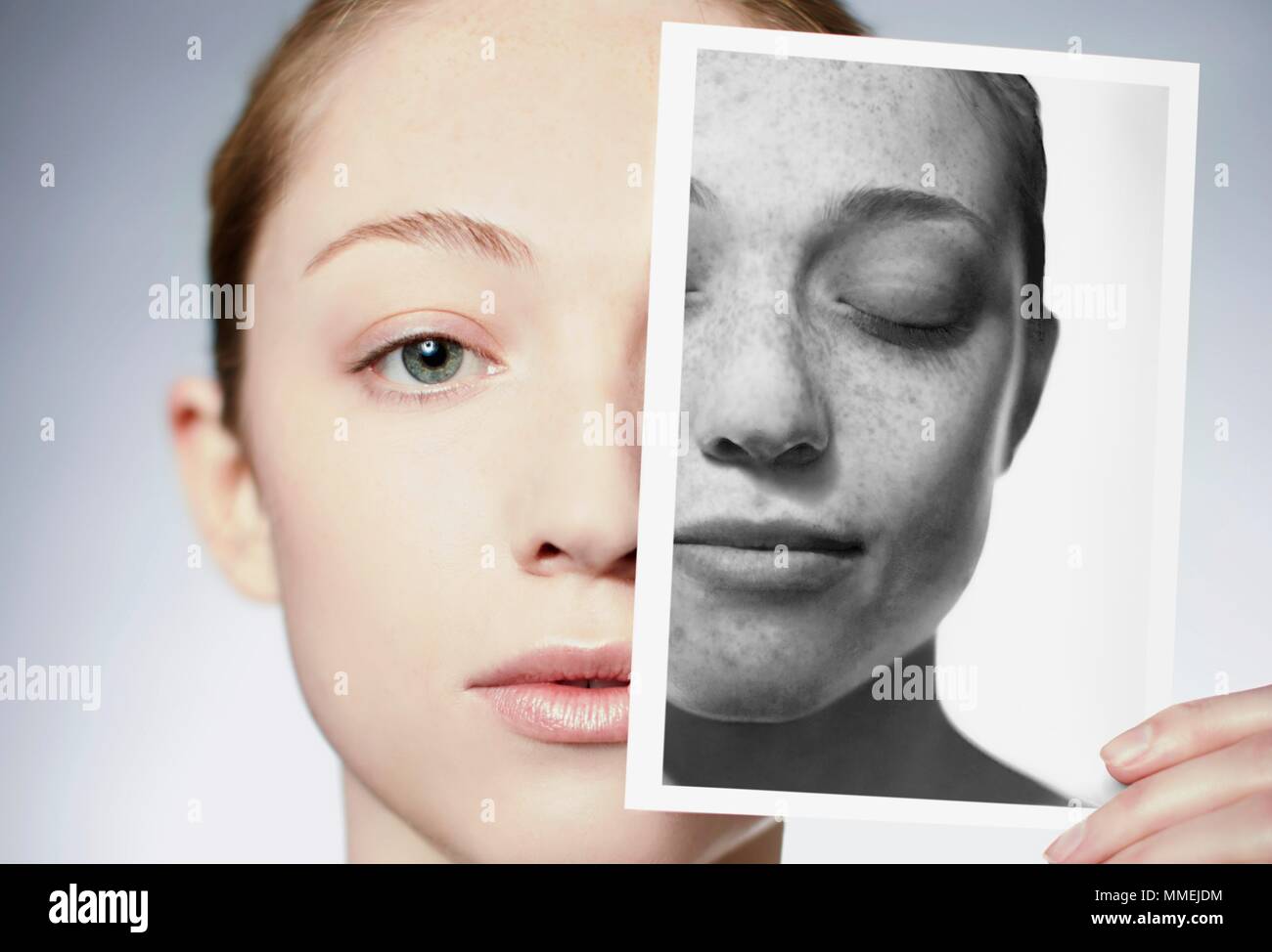 MODEL RELEASED. Sun damage. Woman holding a photograph in front of her ...
