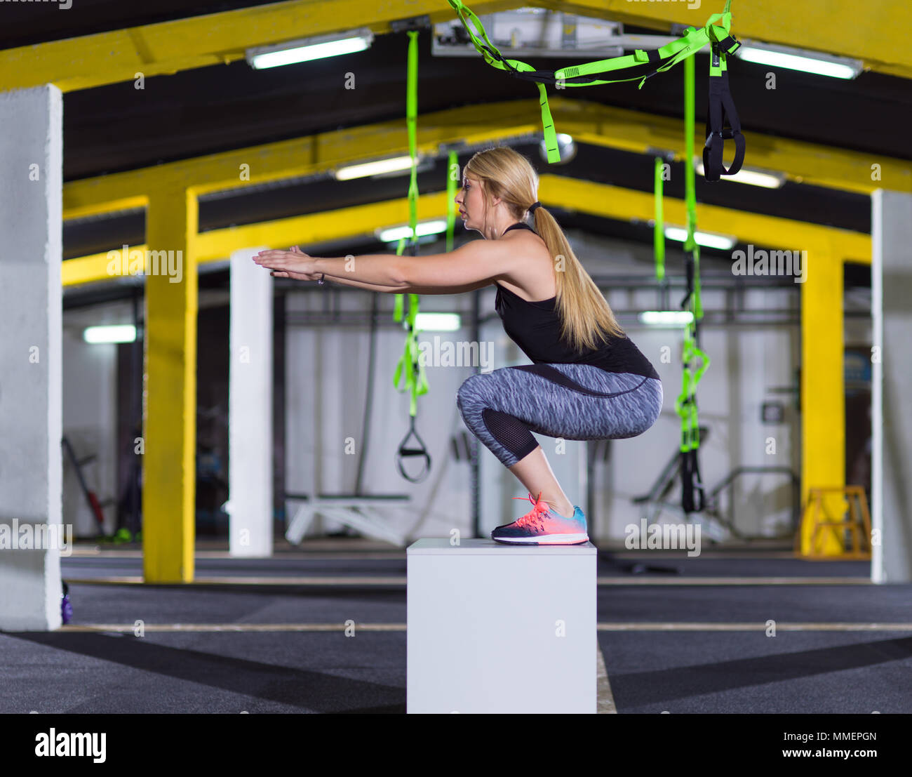 young athletic woman training jumping on fit box at crossfitness gym ...