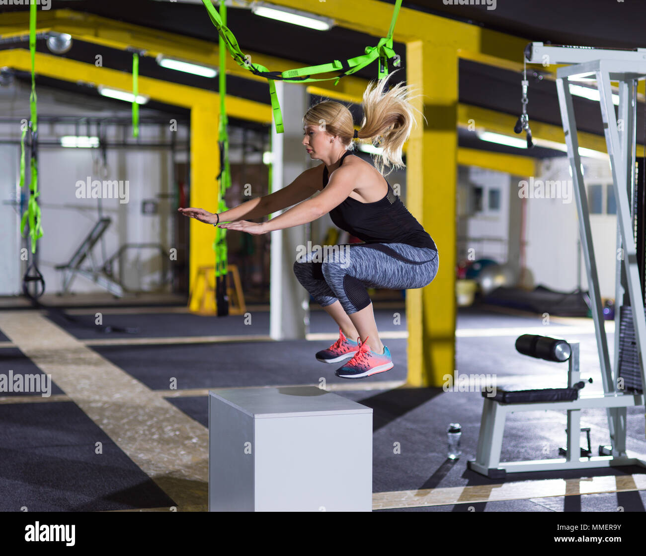 young athletic woman training jumping on fit box at crossfitness gym ...