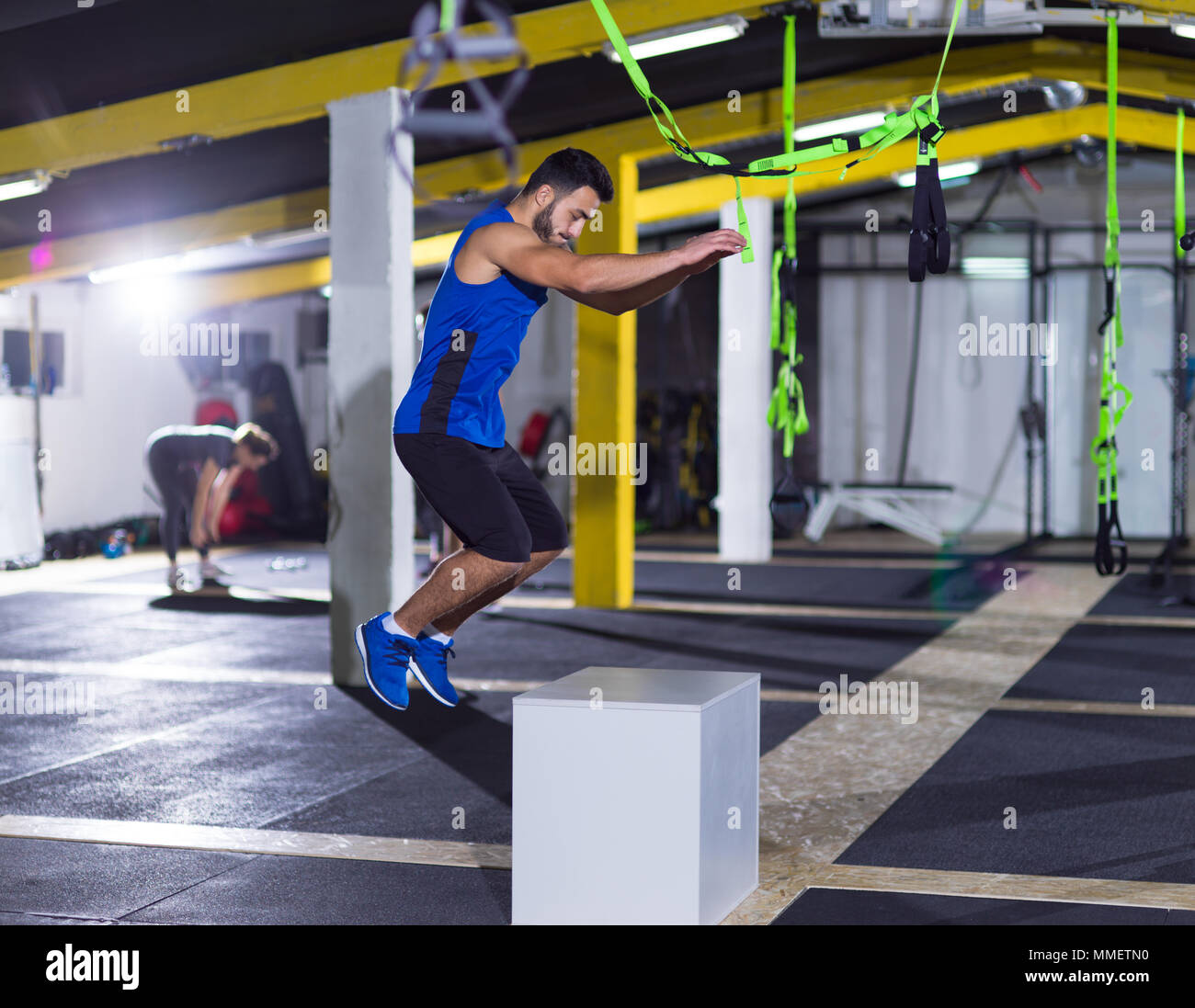 young athletic man training jumping on fit box at crossfitness gym ...
