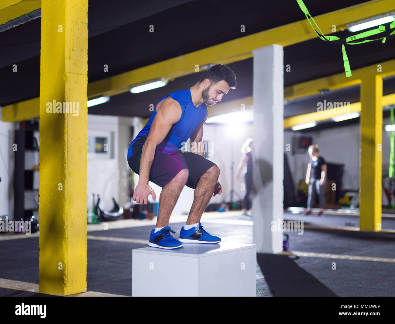 young athletic man training jumping on fit box at crossfitness gym ...