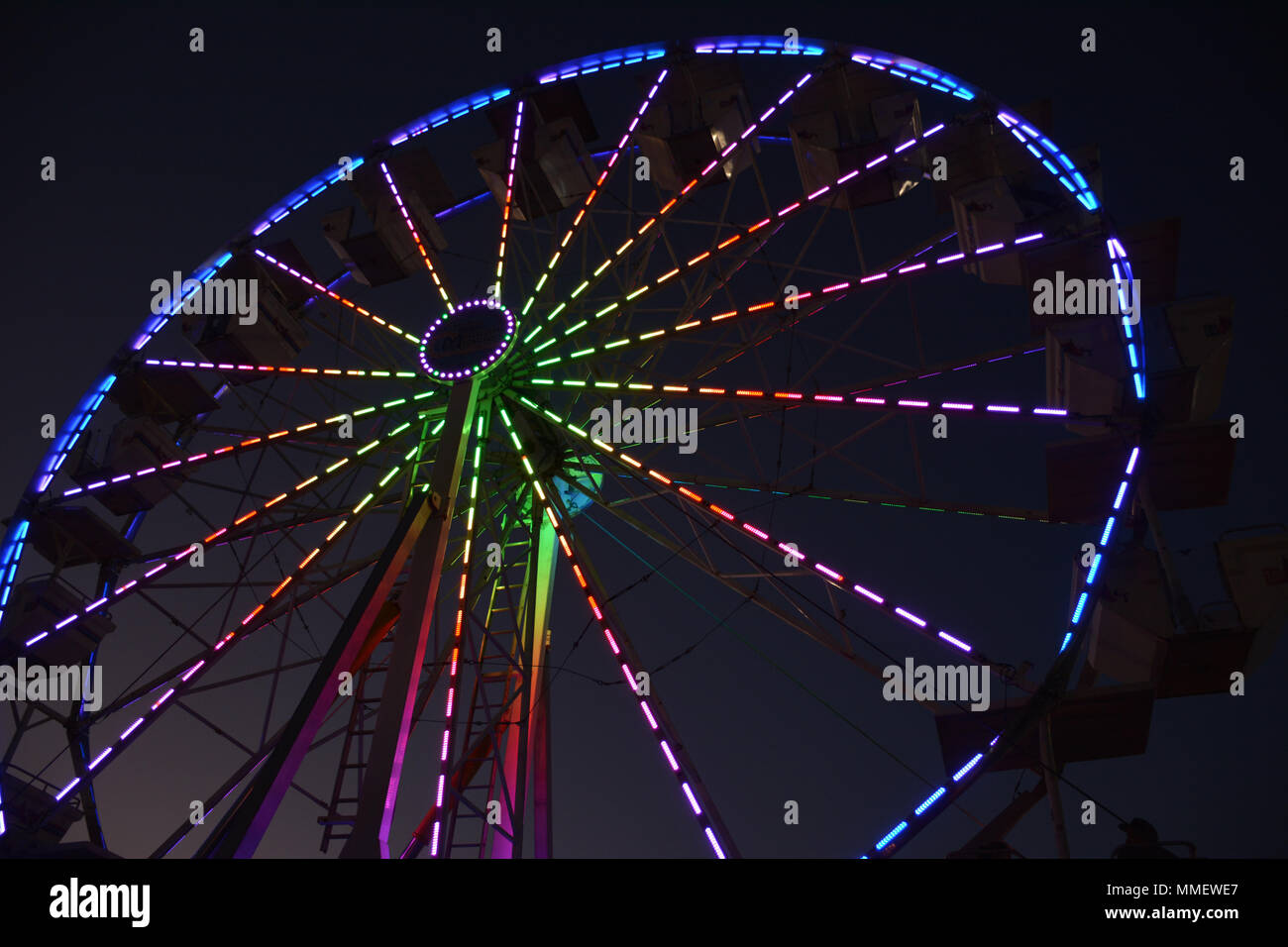The Ferris wheel displays a show of colored lights while carrying ...