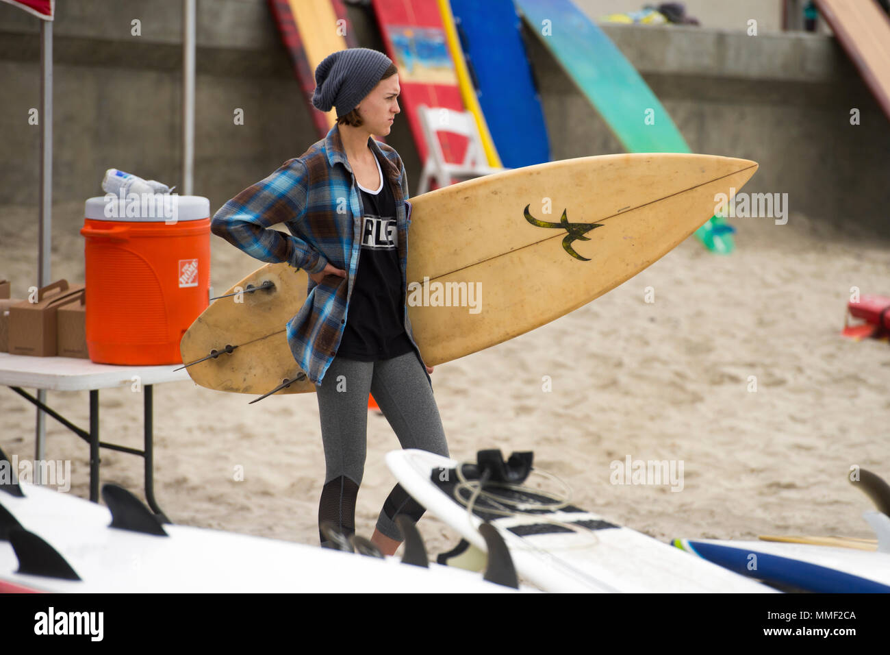 Navy Petty Officer 3rd Class Rachel Duckett holds a surfboard while ...
