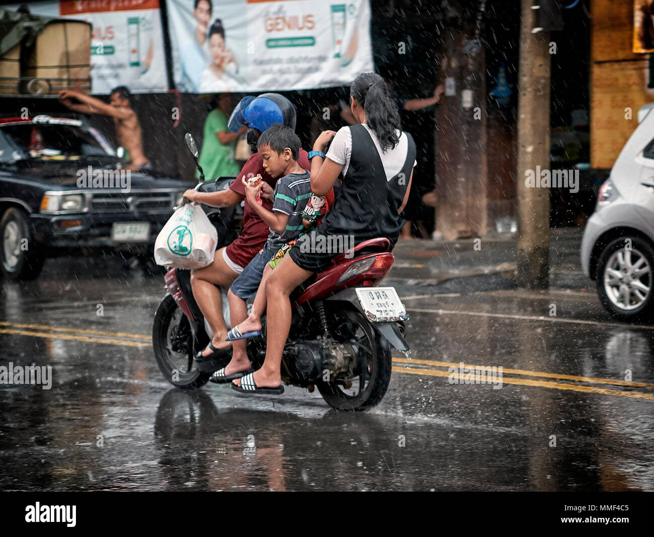 Rain. Thai family on a motorcycle caught in torrential rainfall ...