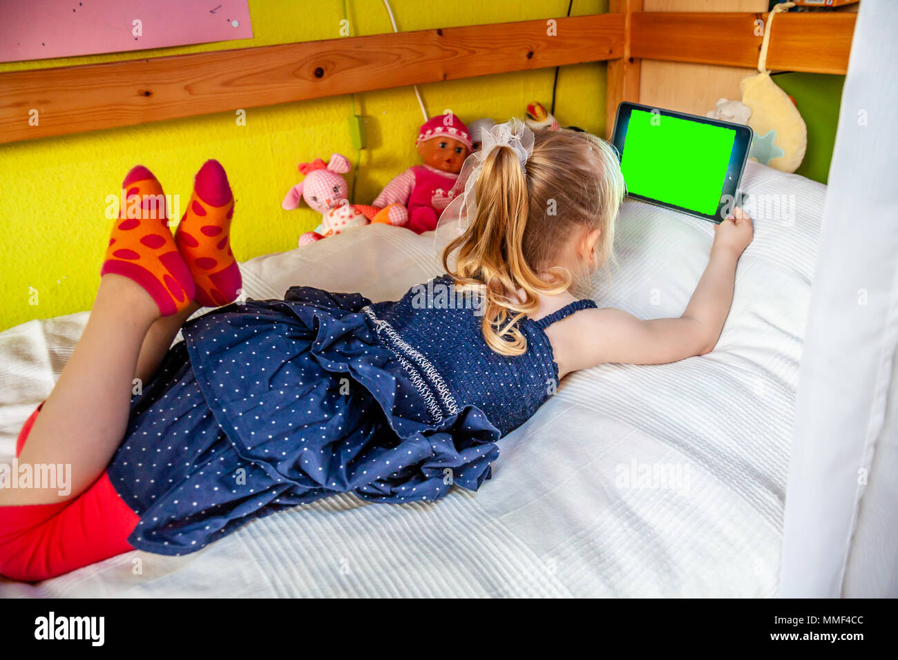Cute little girl lying on bed and using her tablet computer Stock Photo ...