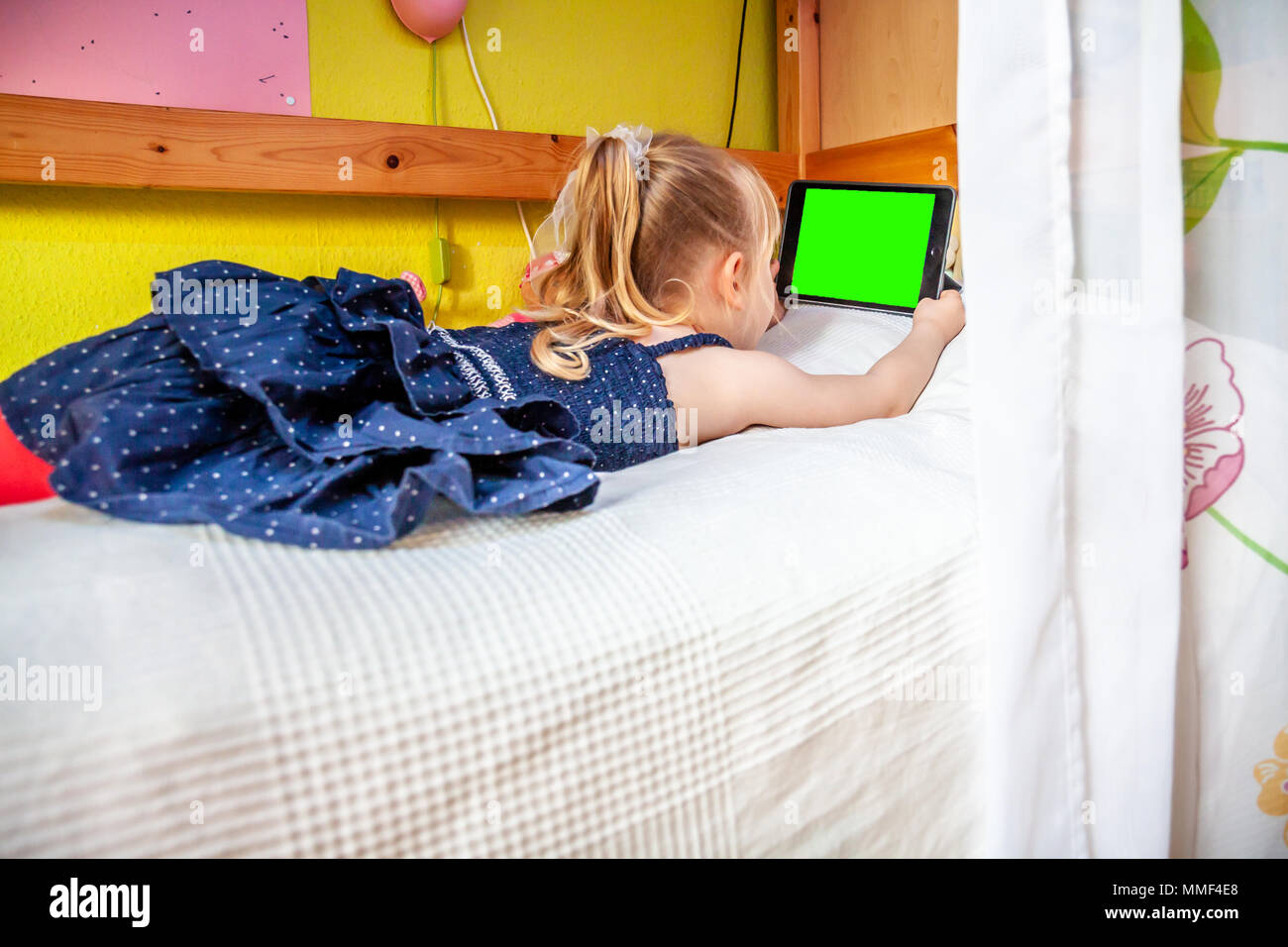 Cute little girl lying on bed and using her tablet computer Stock Photo ...