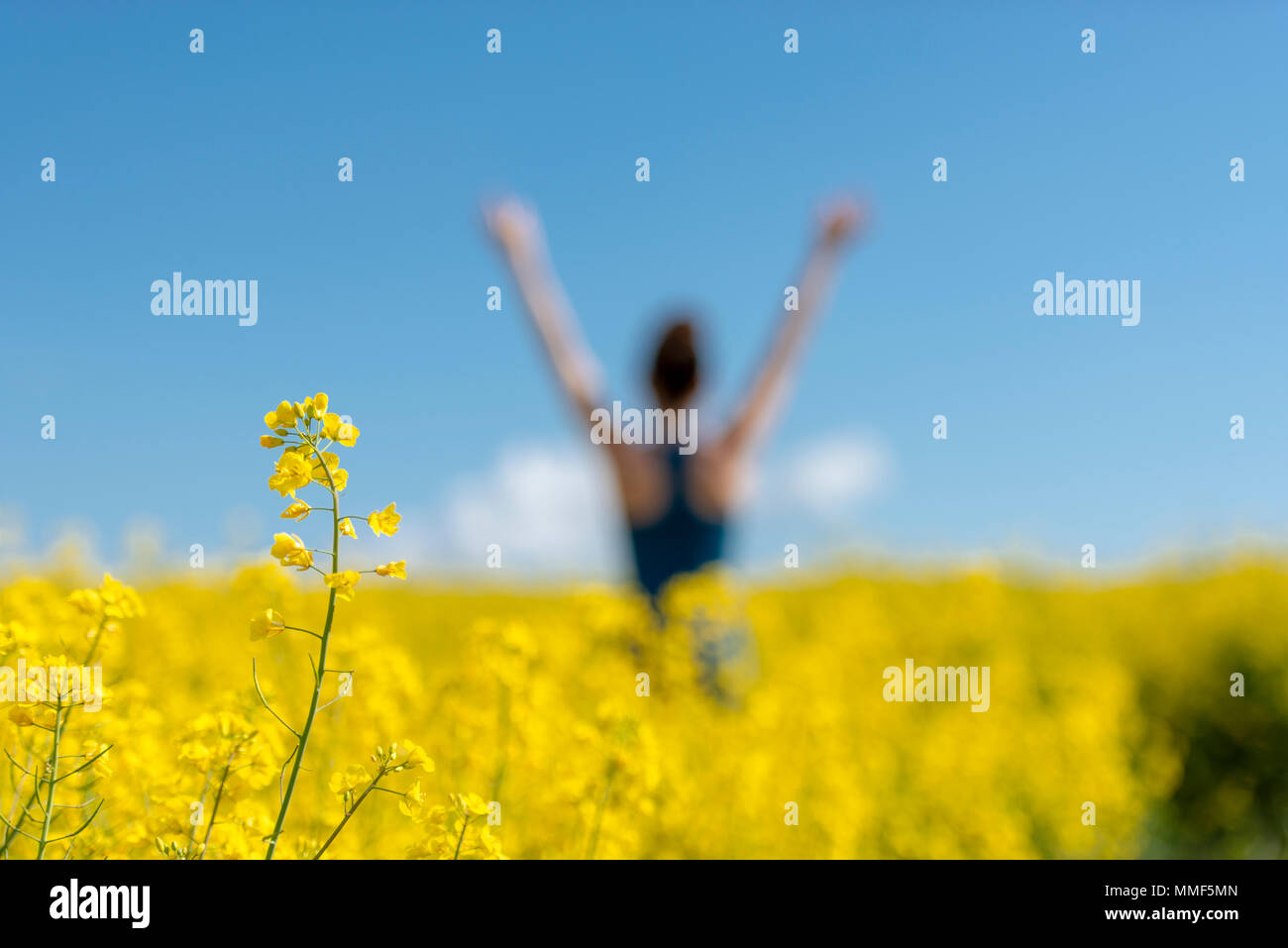 out of focus back view of a young woman with arms raised in a yellow ...