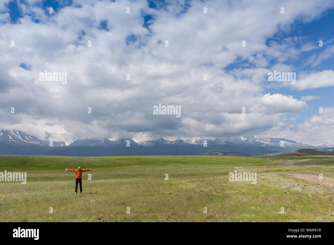 Happy hiker, man stands on a cliff in the prairie, his arms ...