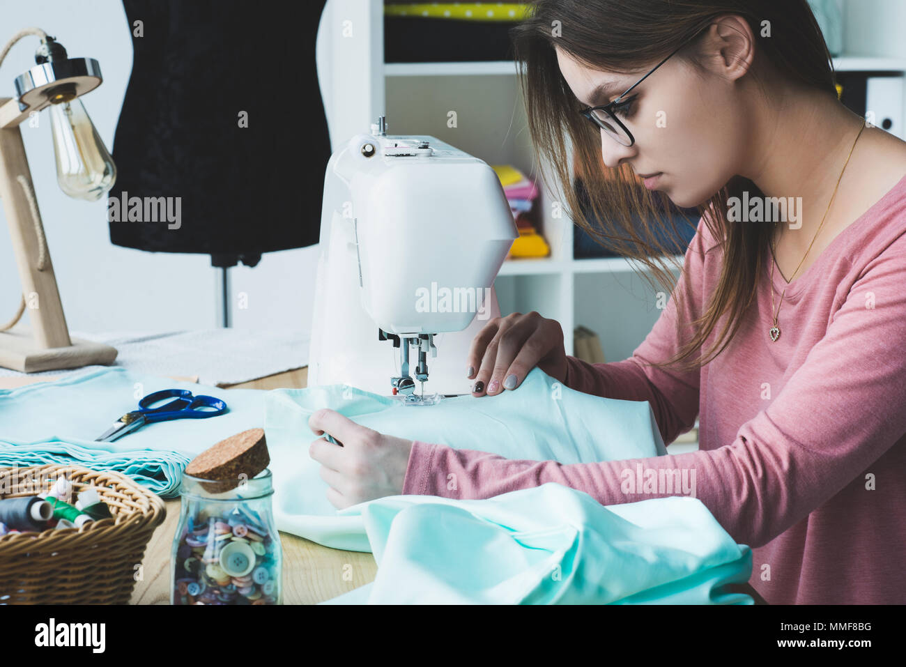 side view of young seamstress using sewing machine at workplace Stock ...