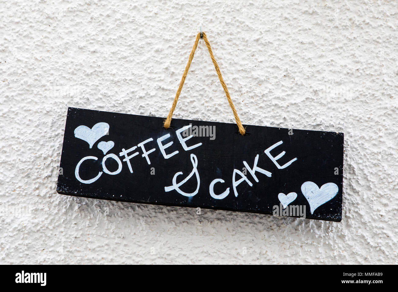 A coffee and cake sign hanging on a wall Stock Photo - Alamy