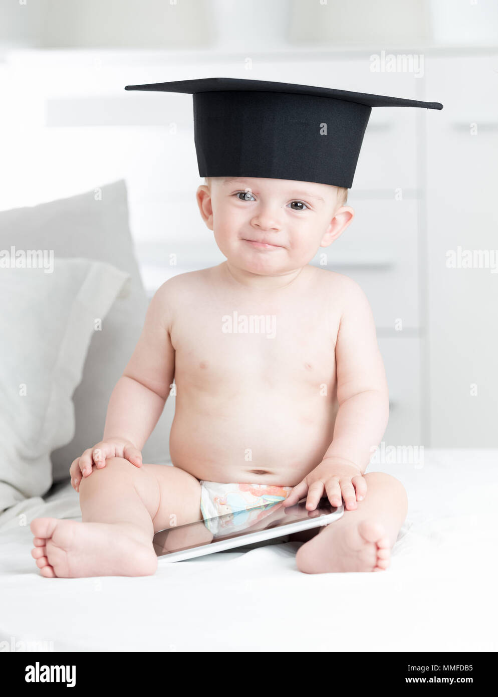 Happy smiling baby boy wearing unifersity graduation cap looking in ...