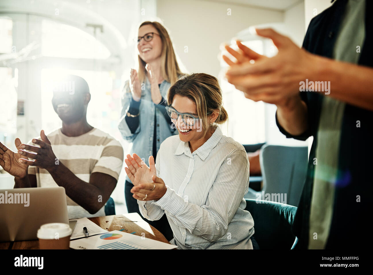 Diverse group of positive businesspeople laughing and clapping during a ...