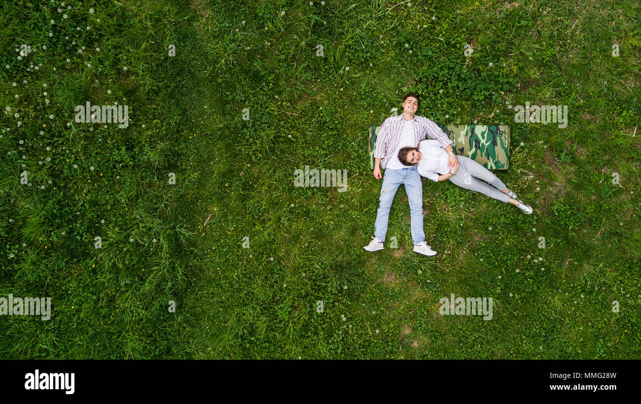 Romantic couple of young people lying on grass in park. They lay on the ...