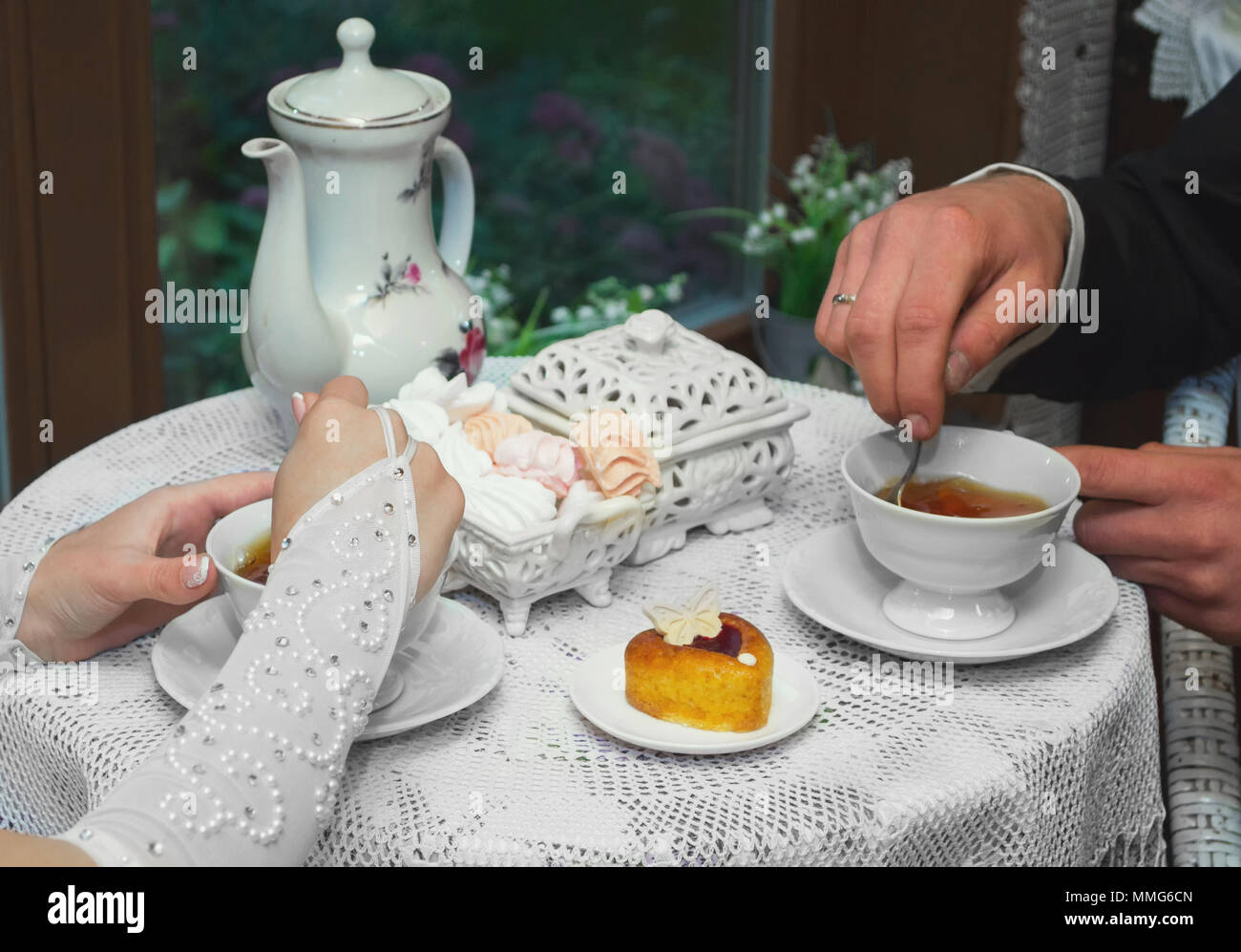The bride and groom sitting at the table in the cafe and drinking tea ...