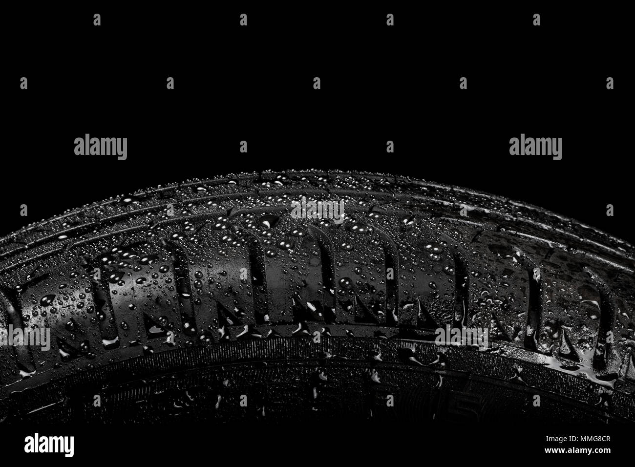 Close up view of a car tyre isolated on a black background with water ...