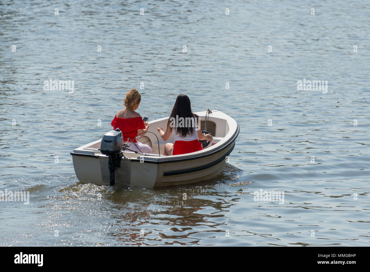 two girls in red and white outfits driving motor boat on river in in ...