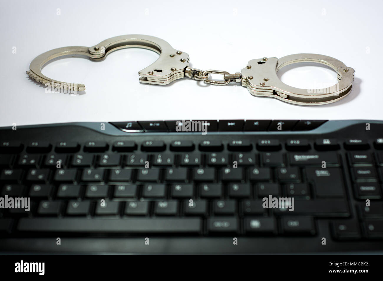 Handcuffs on keyboard Stock Photo - Alamy
