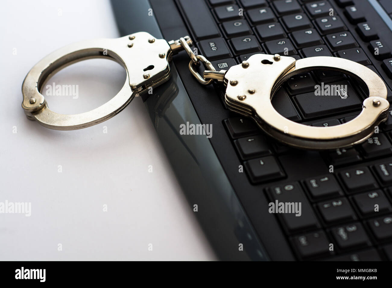 Handcuffs on keyboard Stock Photo - Alamy