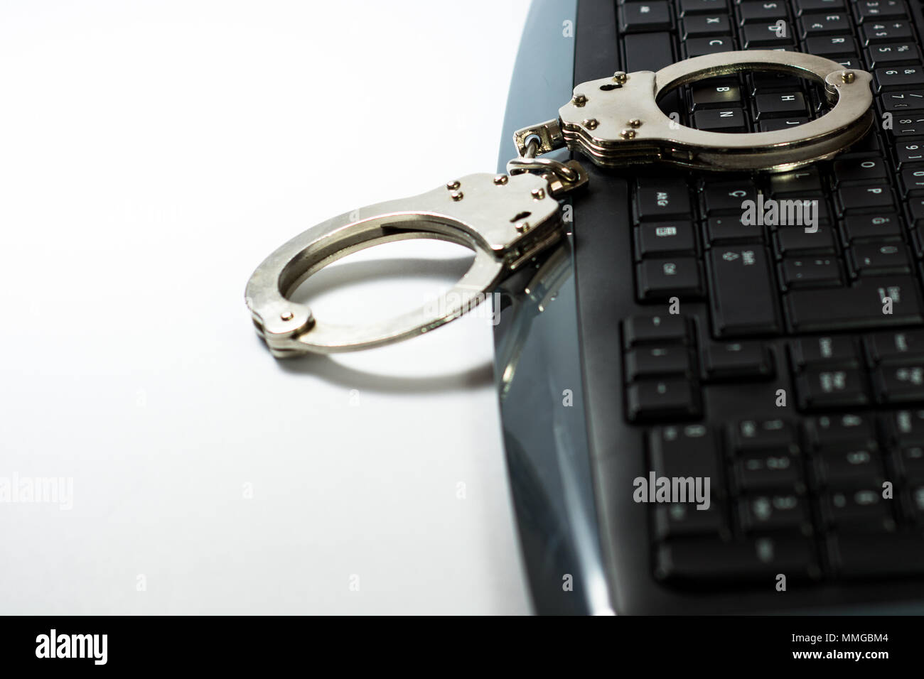 Handcuffs on keyboard Stock Photo - Alamy