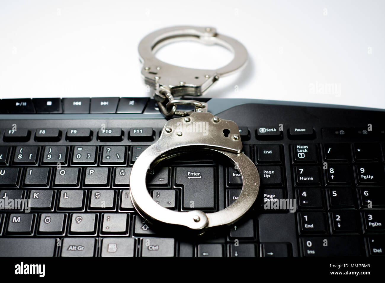 Handcuffs on keyboard Stock Photo - Alamy