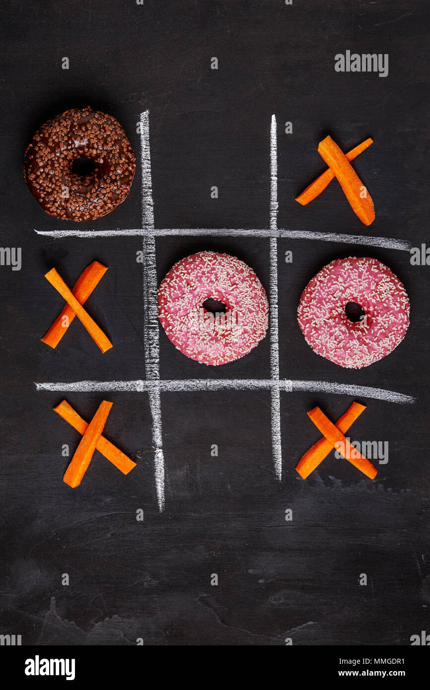 concept idea about junk food and healthy food. tic-tac-toe carrots and ...