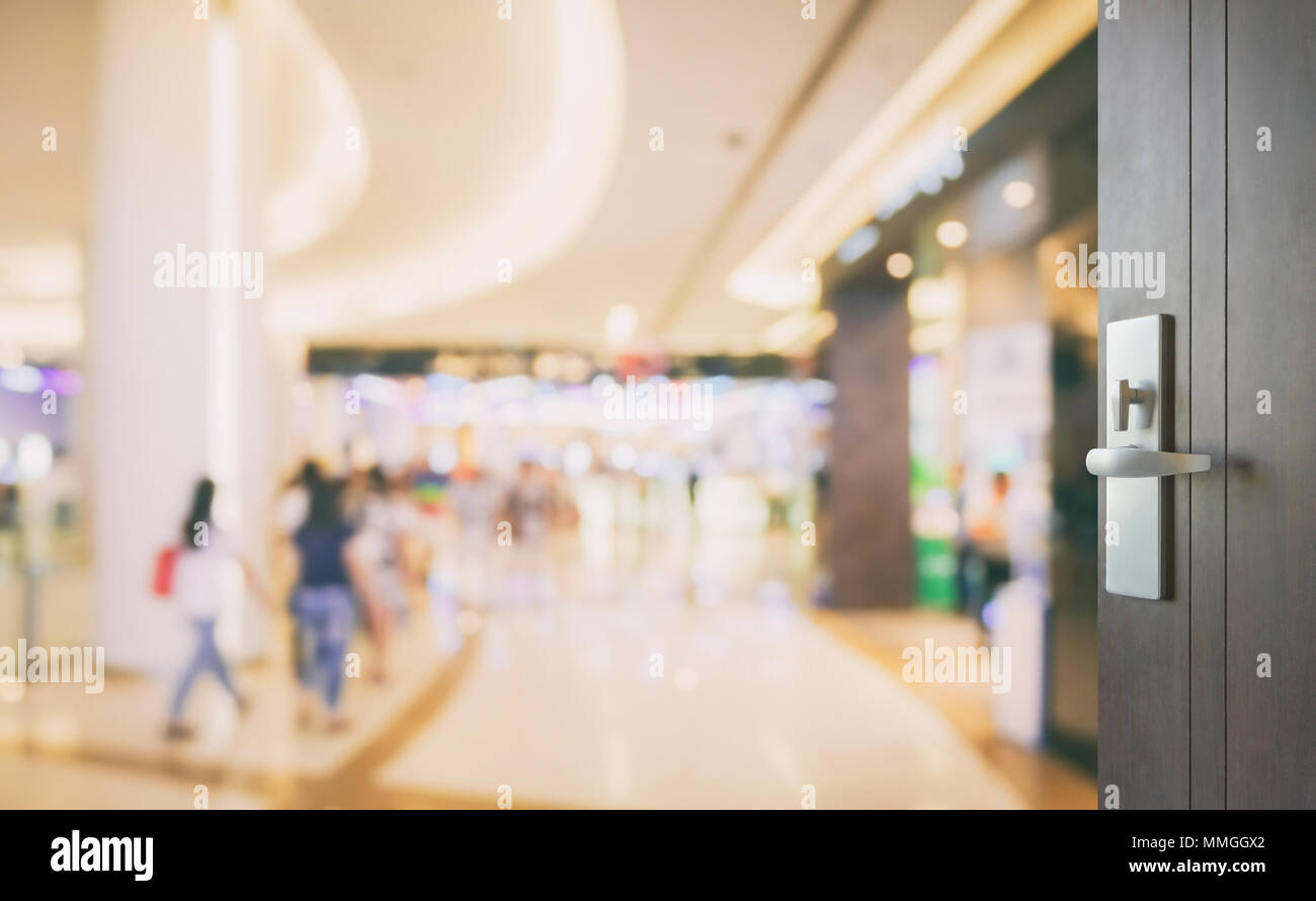 opened wooden door to department store with people shopping as ...