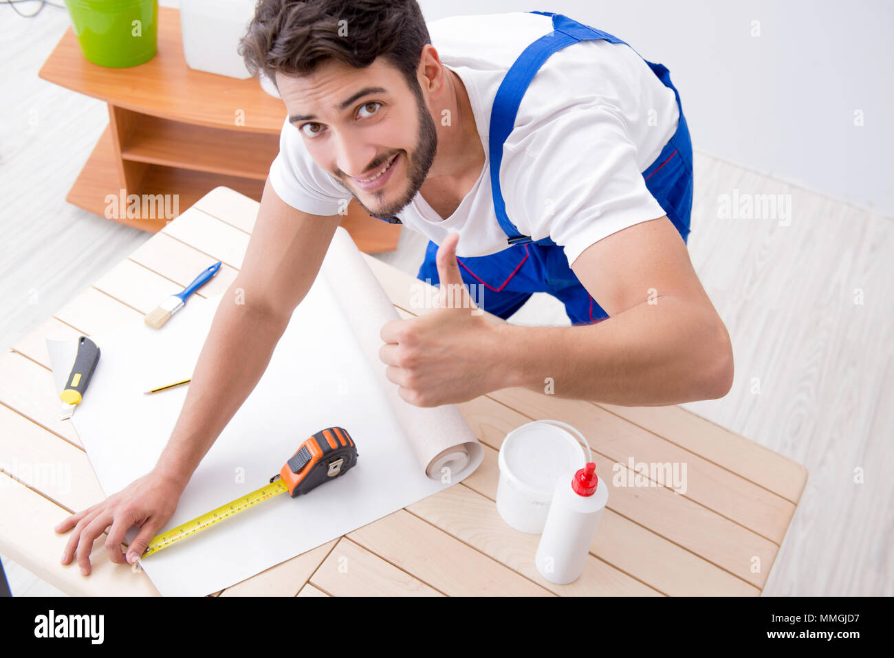 Worker working on wallpaper during refurbishment Stock Photo - Alamy
