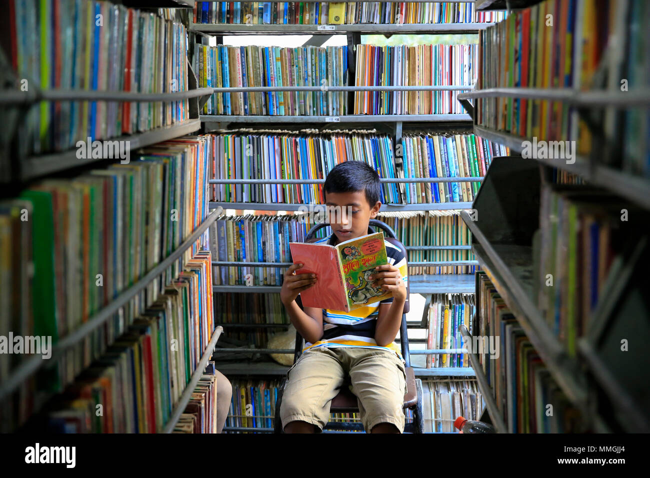 A boy reading a book in a Mobile Library of Bishwo Shahitto Kendro ...