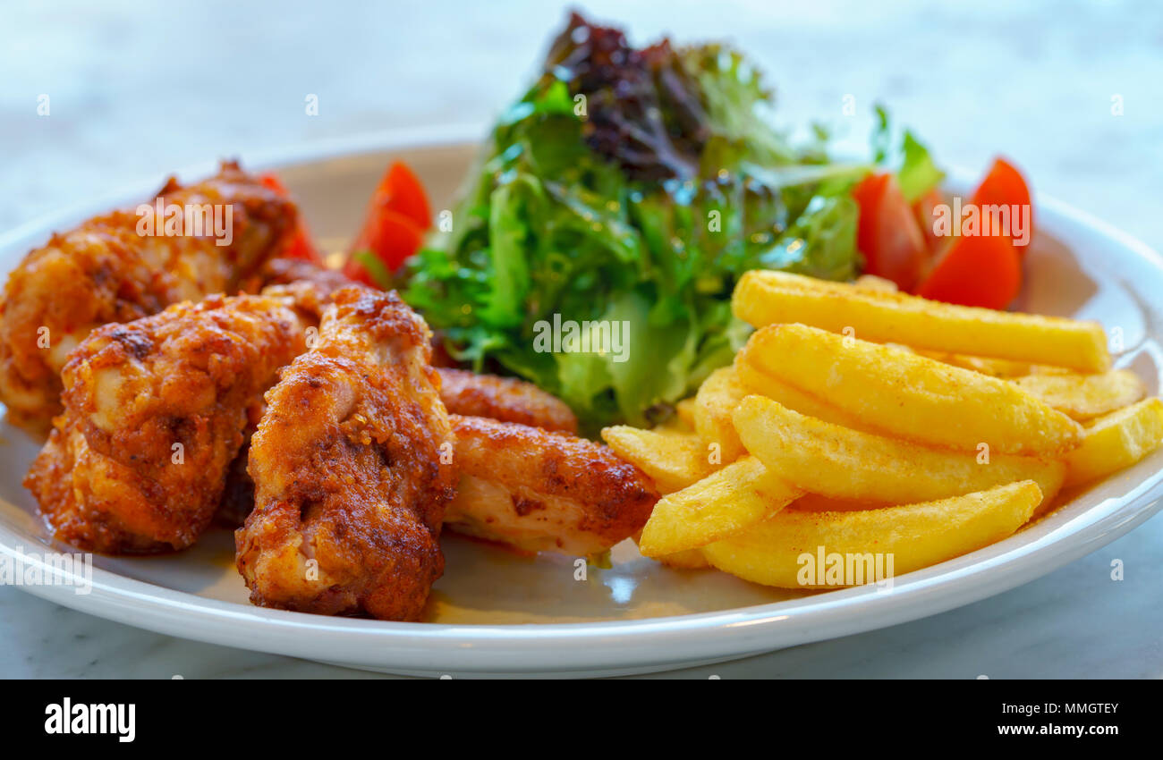 Turkish style chicken wings served with potato fries and salad Stock ...