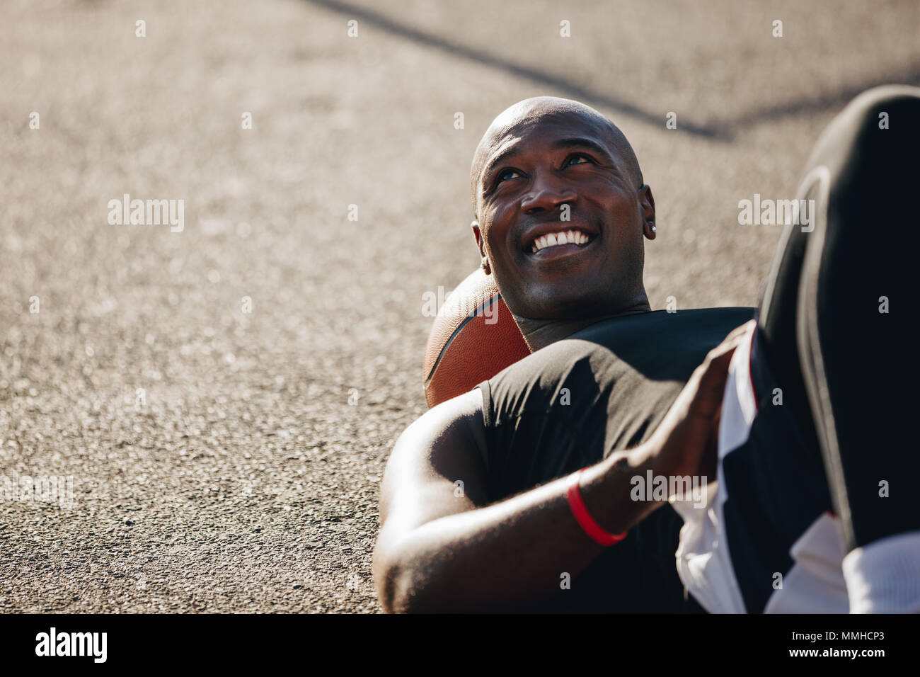Man taking a break during a game of basketball. Man resting on ground ...