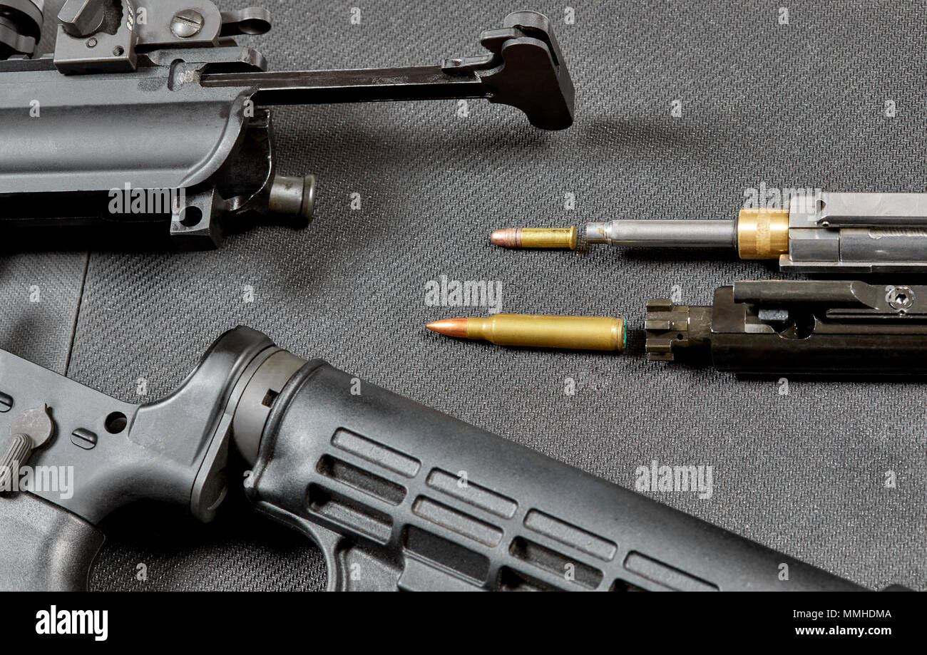 A disassembled AR15 rifle laying on a table with a 22 mm cartridge ...
