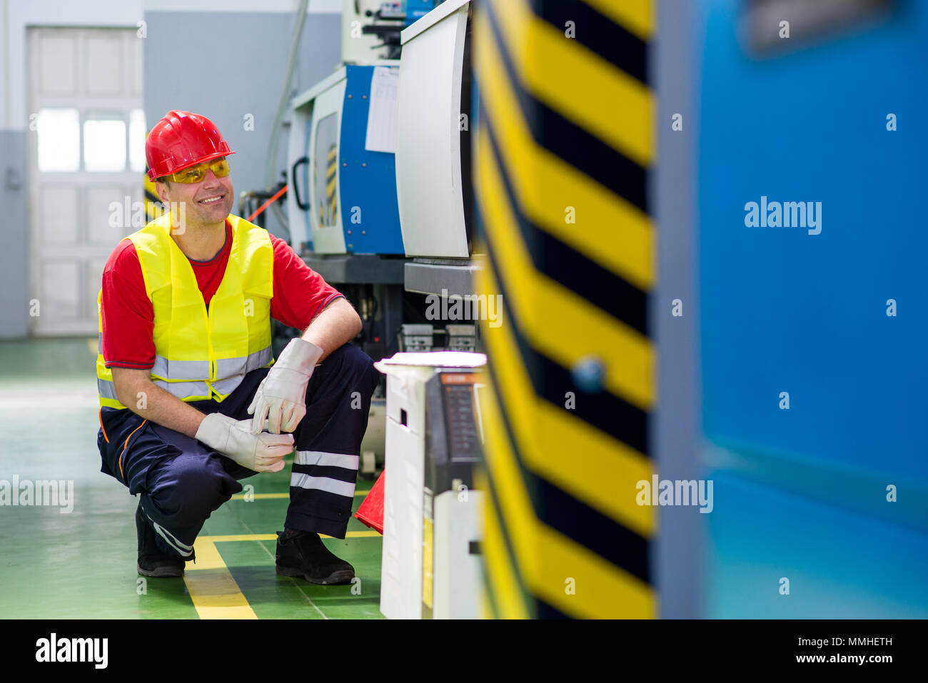 Worker in a factory. Worker wearing reflective west and red helmet ...