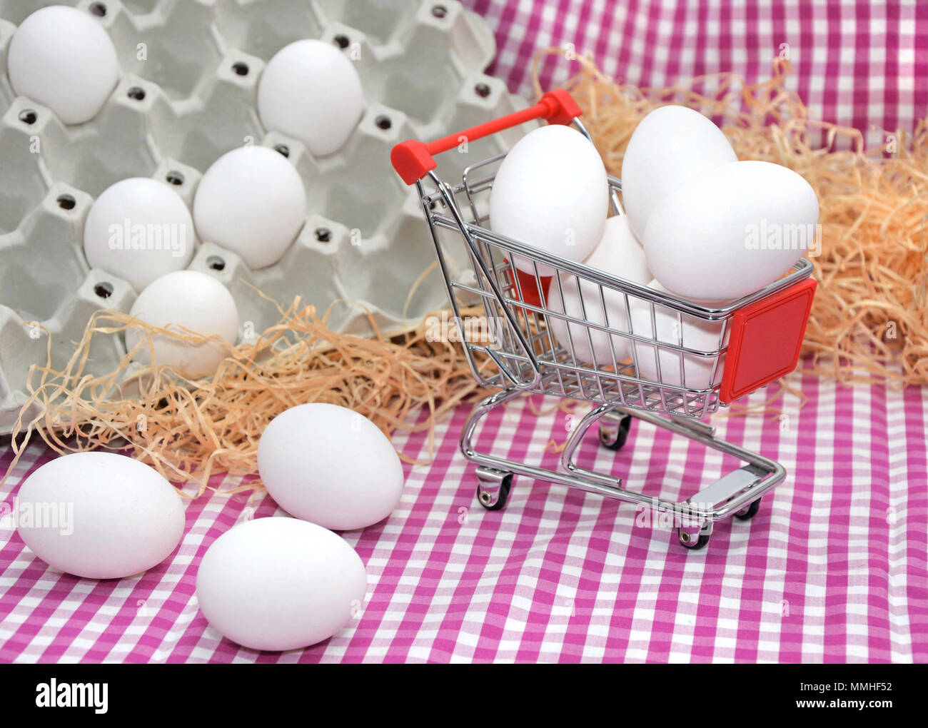 Shopping cart with white chicken eggs and a egg crate on a checkered ...