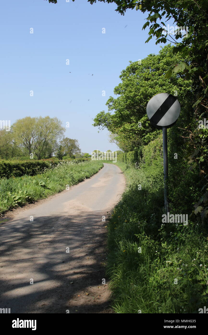 a deserted country lane with an end of speed restrictions sign Stock ...