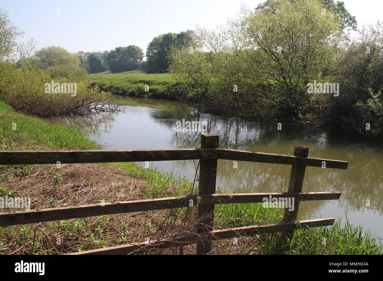 a fence end leading down to a picturesque stretch of river surrounded ...