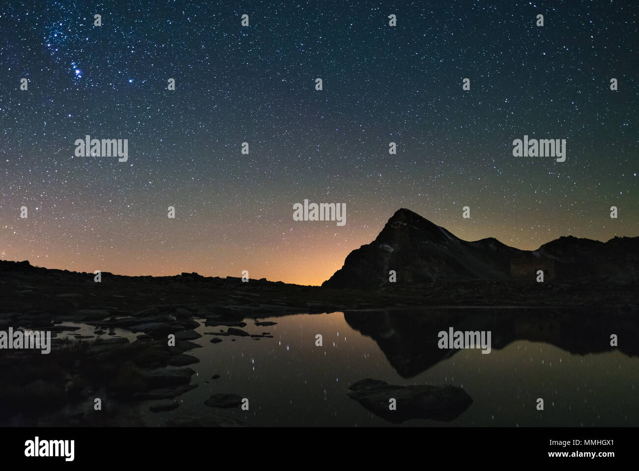 Astro starry sky reflected on lake at high altitude on the Alps. Orion ...