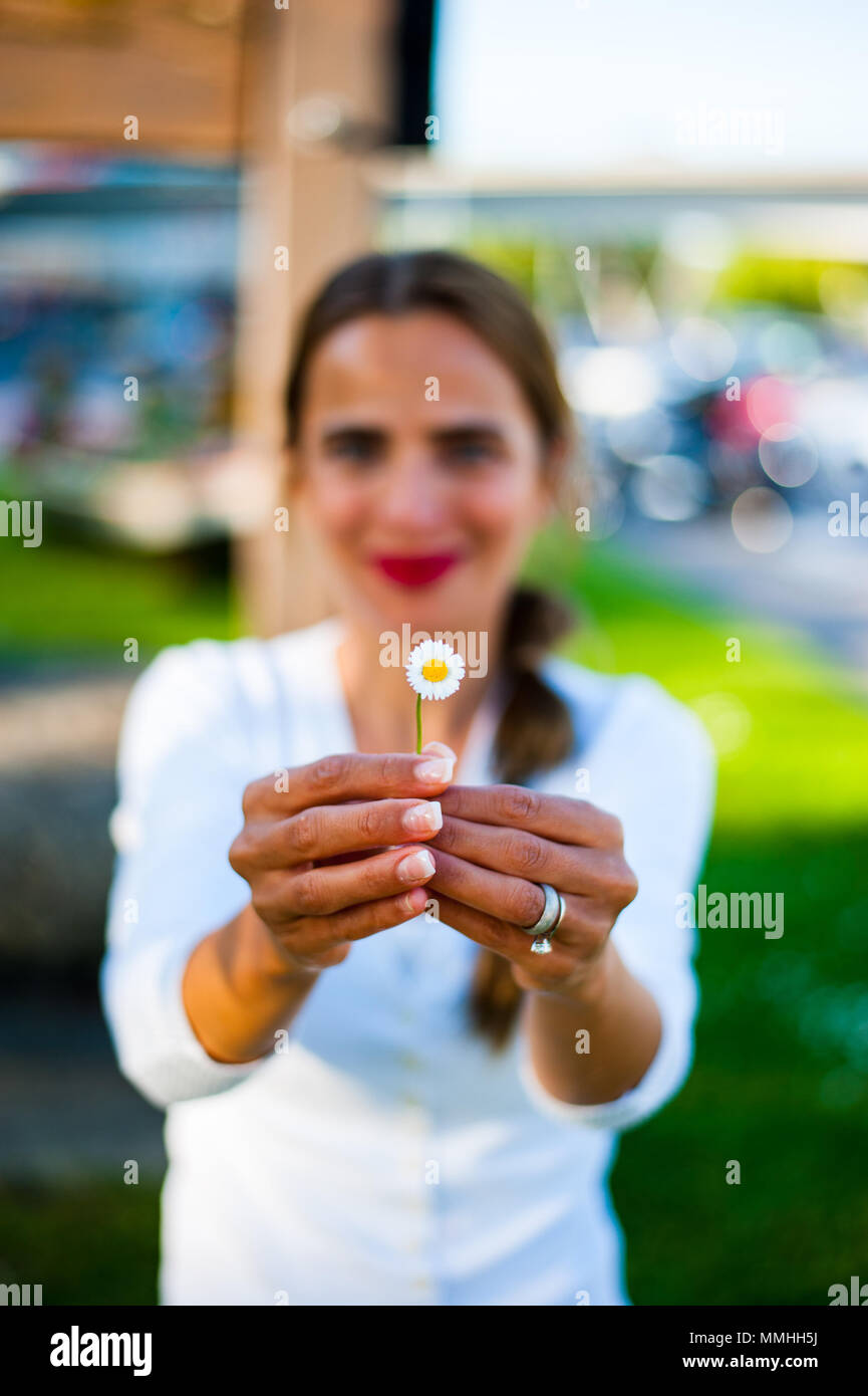 Beautiful woman holding a daisy in her hands Stock Photo - Alamy
