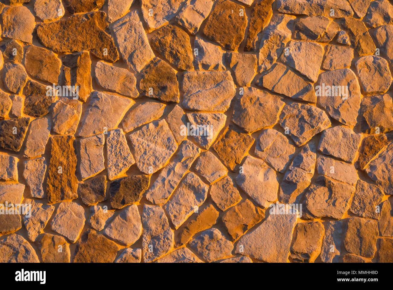Close up view of a stone wall illuminated by late afternoon sunlight ...