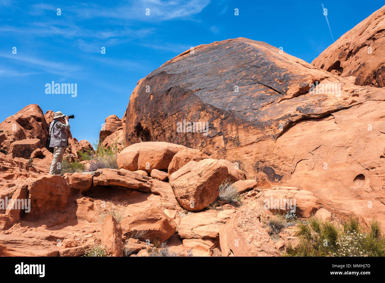 Visitor photographing symbols etched in red Aztec sandstone rock ...
