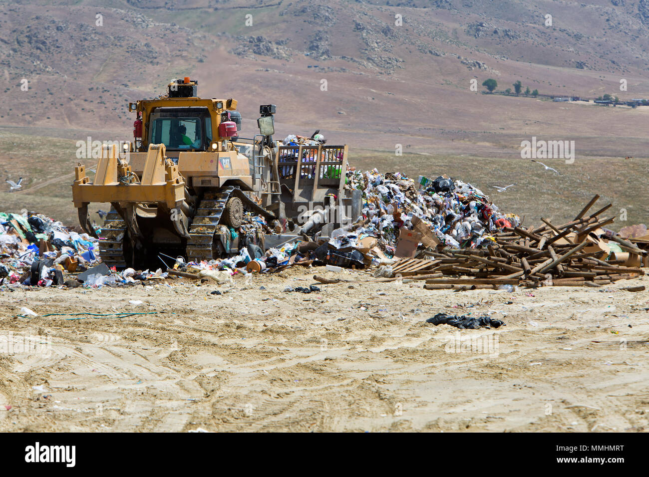 Driver operating Caterpillar Track Laying Dozer pushing trash, sanitary ...