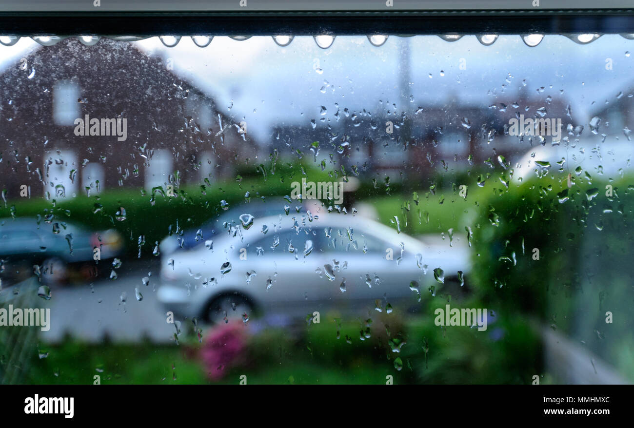Car passing in rainy city street seen through glass window Stock Photo ...